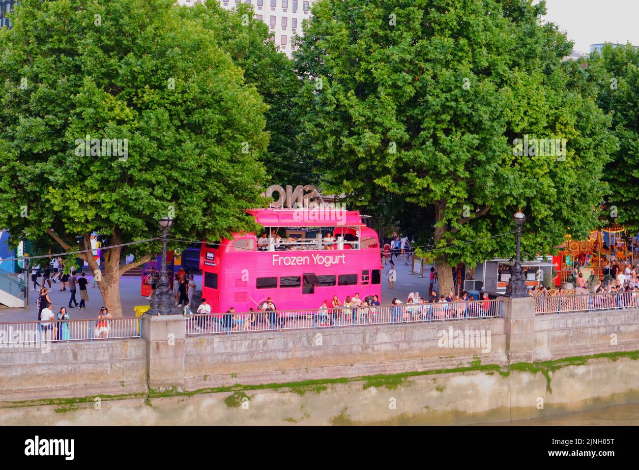 A pink commercial bus and people on the walkway in the London South ...