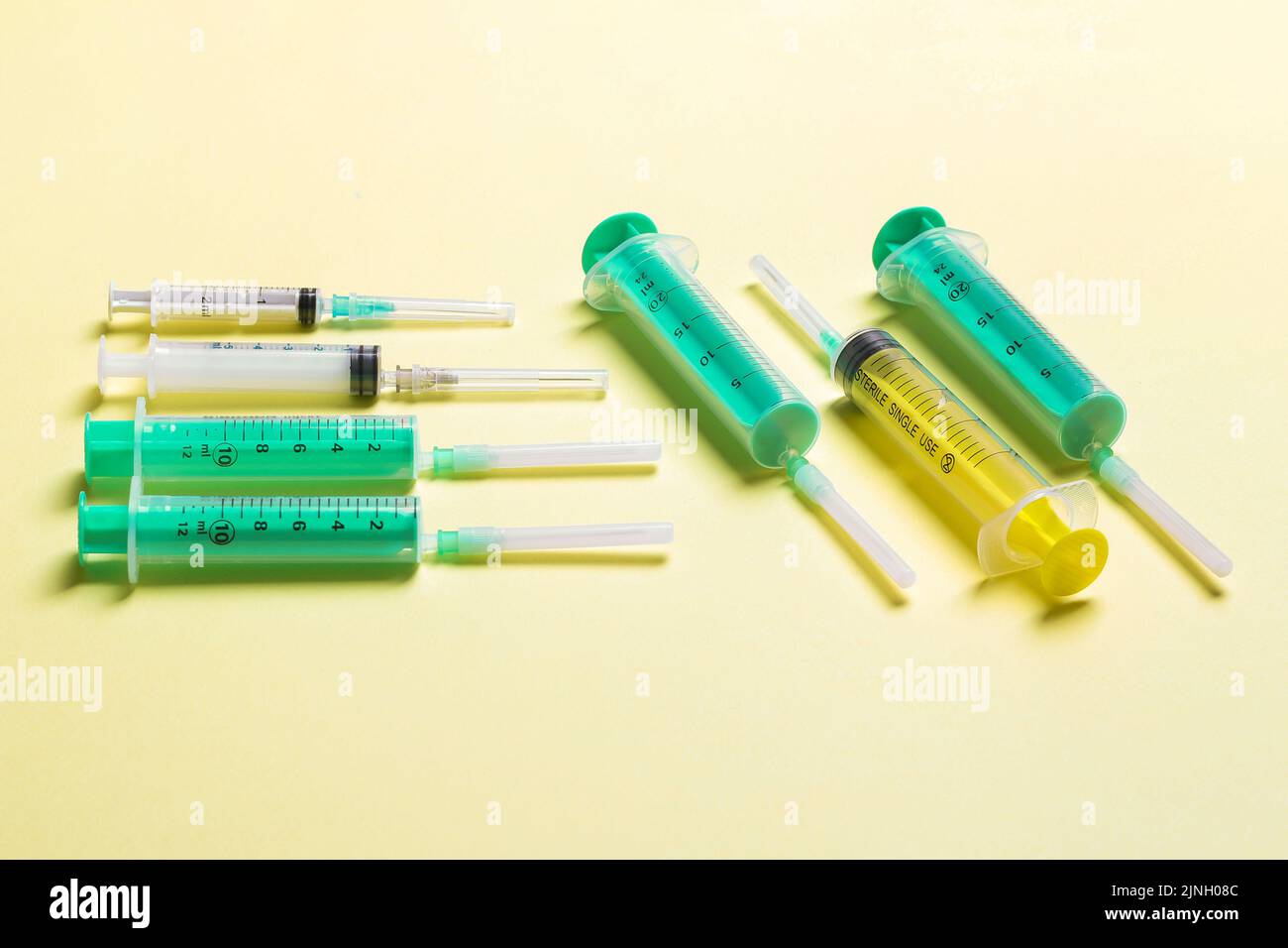 Top view of medical syringes with needles at yellow background with ...