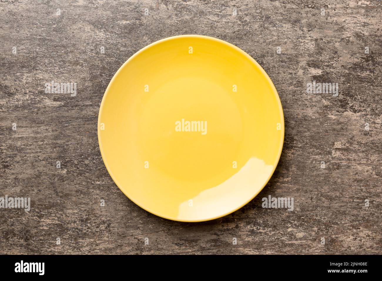 Top view of empty yellow plate on cement background. Empty space for ...