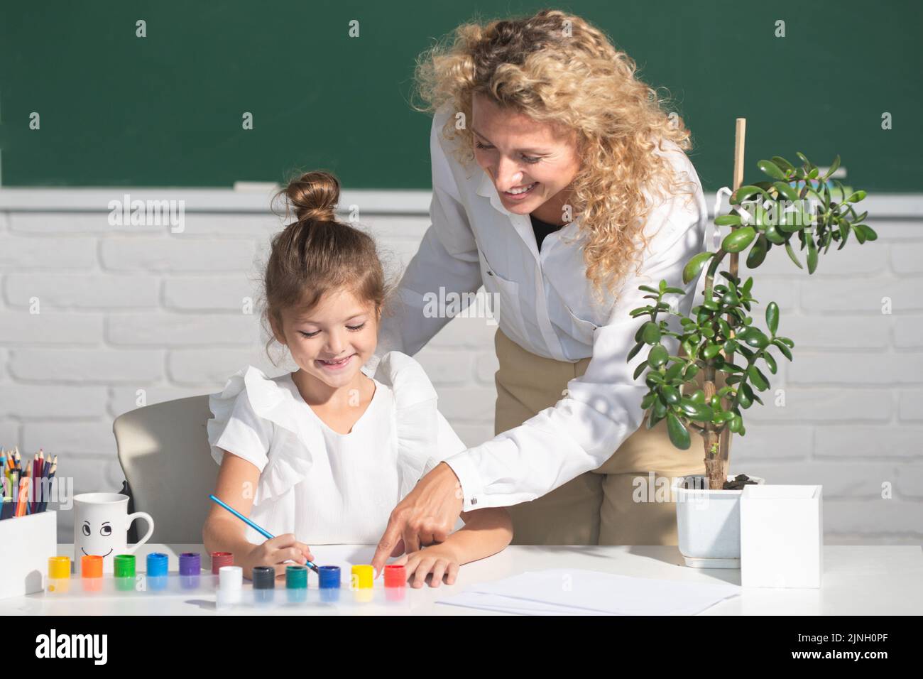 School girl drawing with teacher. Children from elementary school study ...