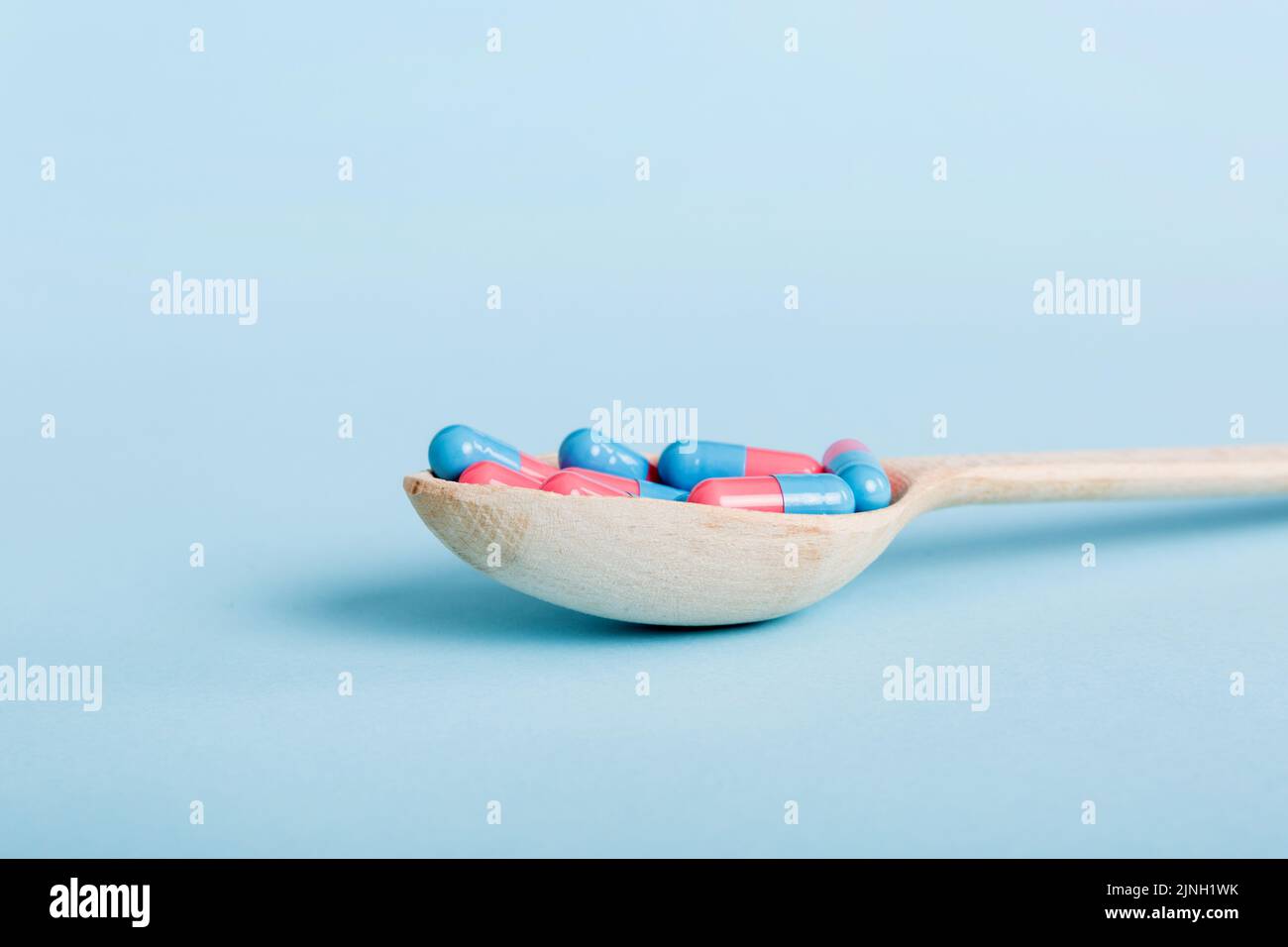 Vitamin capsules in a spoon on a colored background. Pills served as a ...