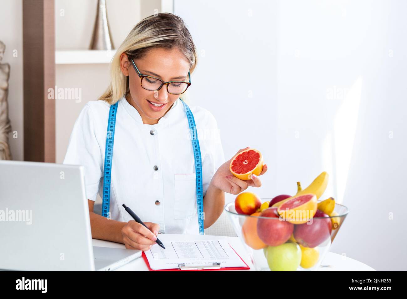 Portrait of young smiling female nutritionist in the consultation room ...