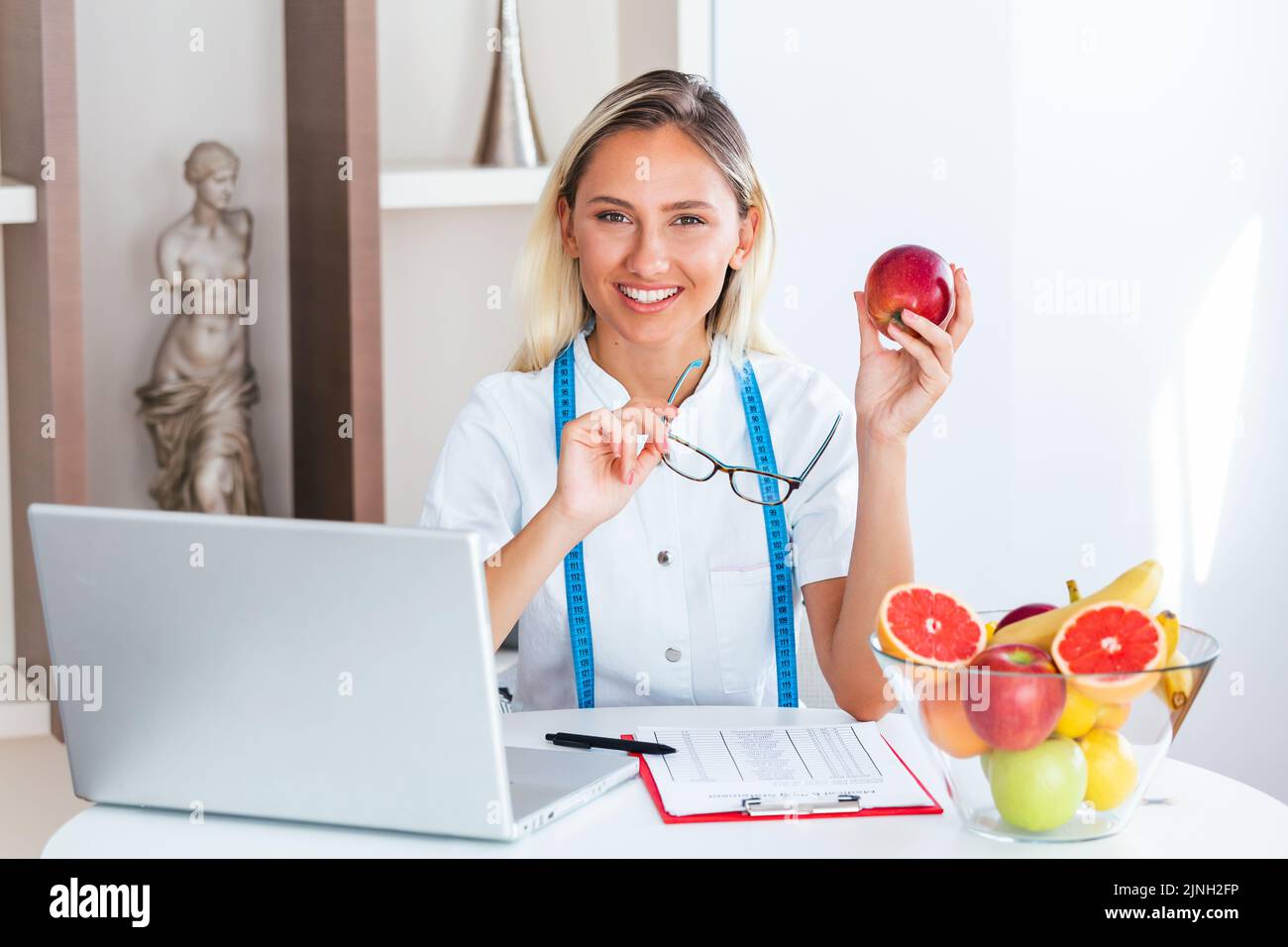 Portrait of young smiling female nutritionist in the consultation room ...