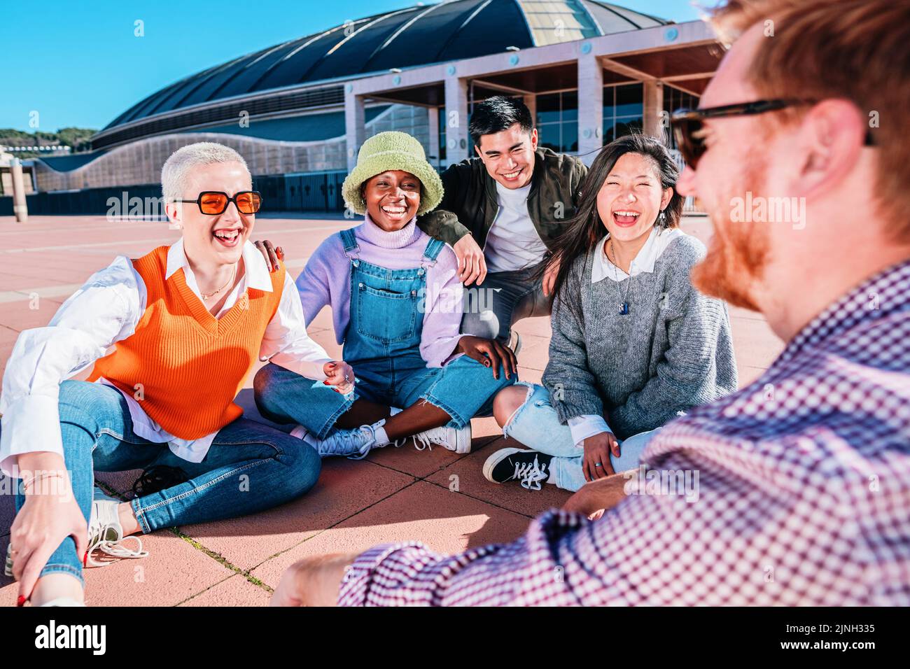 young group of friends laughing sitting together on the floor outdoor ...