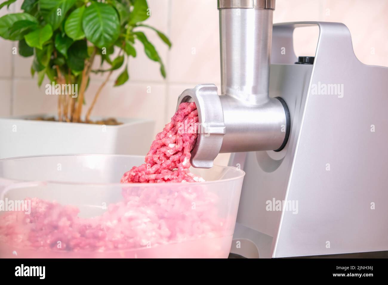 A man processes meat in an electric meat grinder. Preparation of minced ...