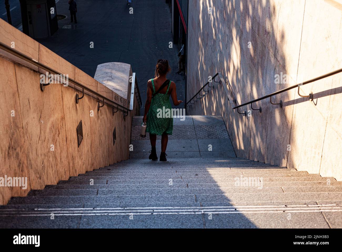 Rear view of young woman coming down stairs in Paris. City tourism ...
