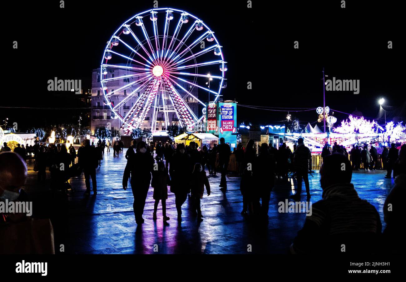 The lights of a wheel in St. George's Square with silhouettes of ...