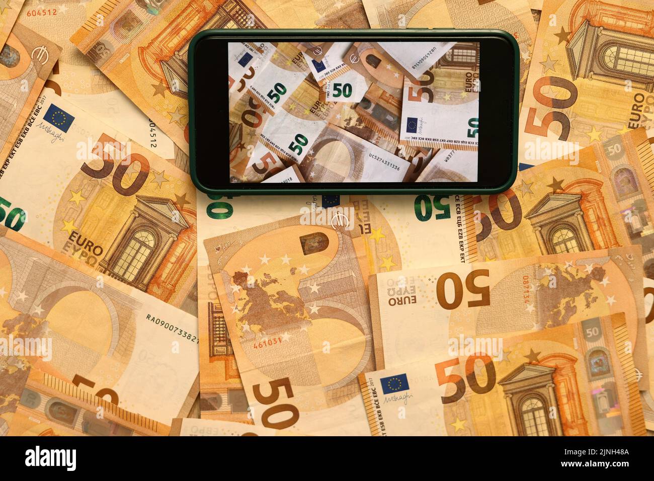 Money paper 50 euro banknotes on the background of a smartphone screen ...
