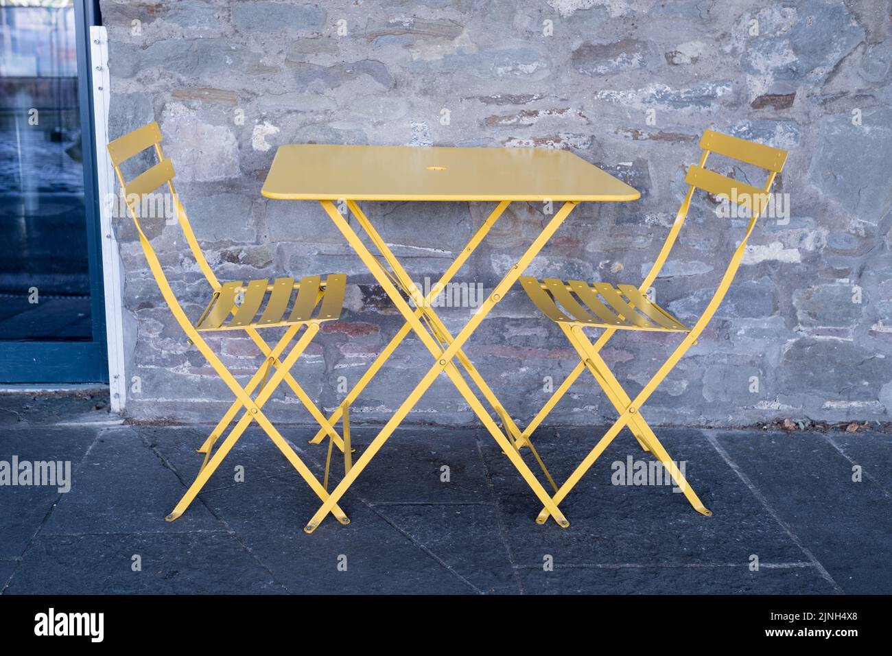 Simple, yellow painted cafe table & two chairs Stock Photo - Alamy