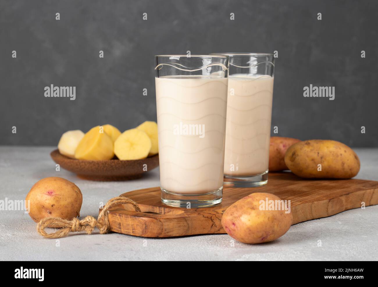 Vegan potato milk in two glass and potato in plate on gray background ...