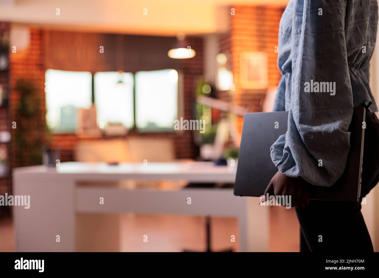 Female remote worker holding laptop in home office with modern interior ...