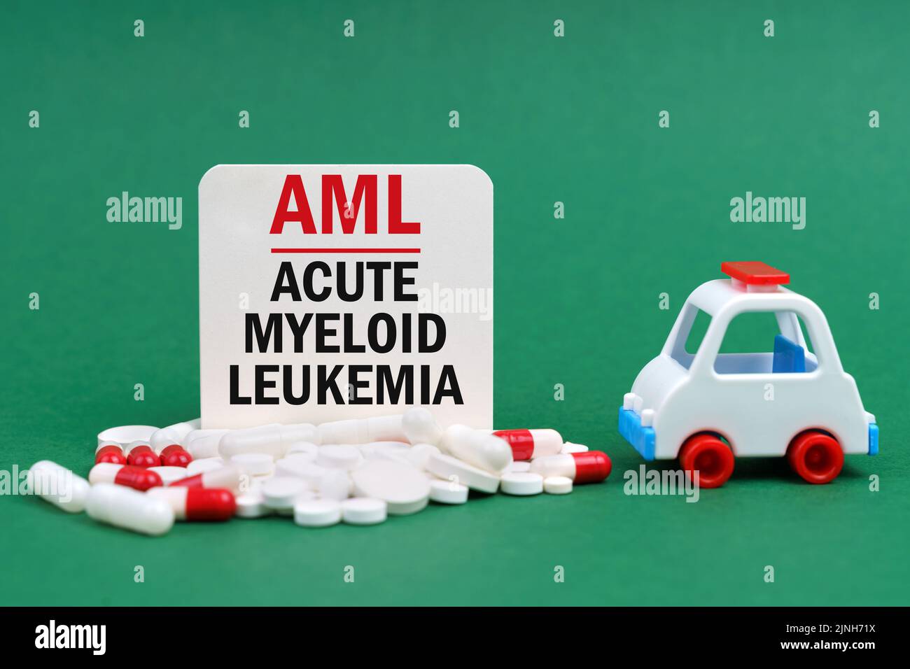 Medical concept. On a green surface, an ambulance, pills and a white ...
