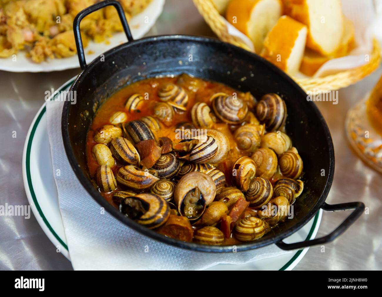 Grape snails in sauce. Spanish dish Stock Photo - Alamy