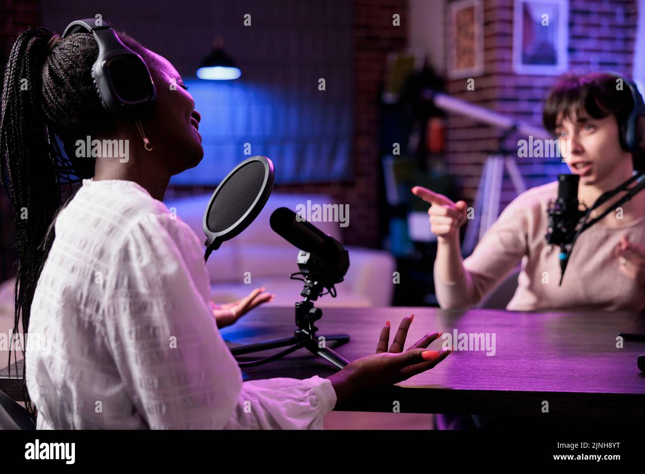 Diverse team of women meeting in studio to talk on podcast, recording ...