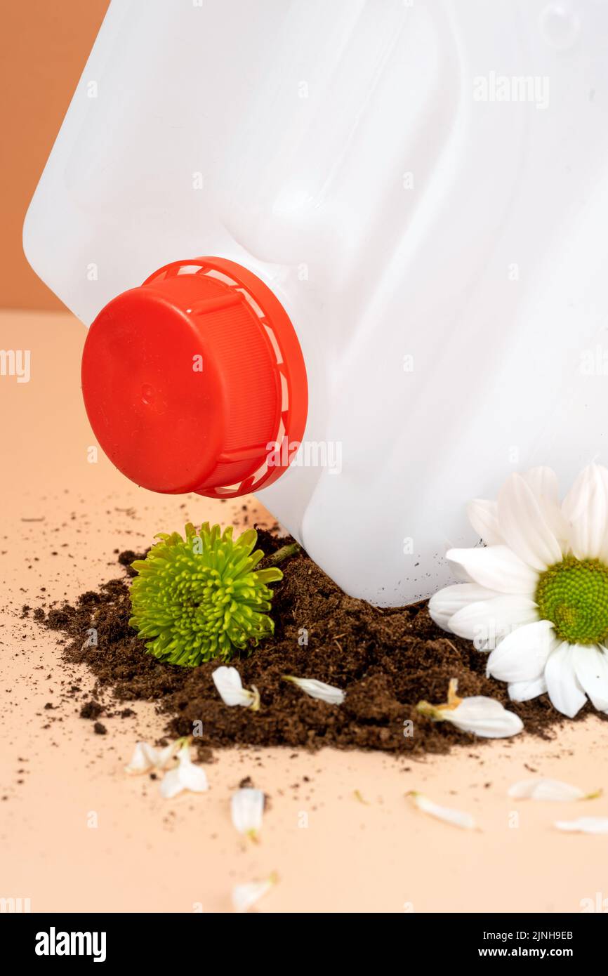 Negative impact on nature. Plastic jerrycan crushes beautiful flowers ...