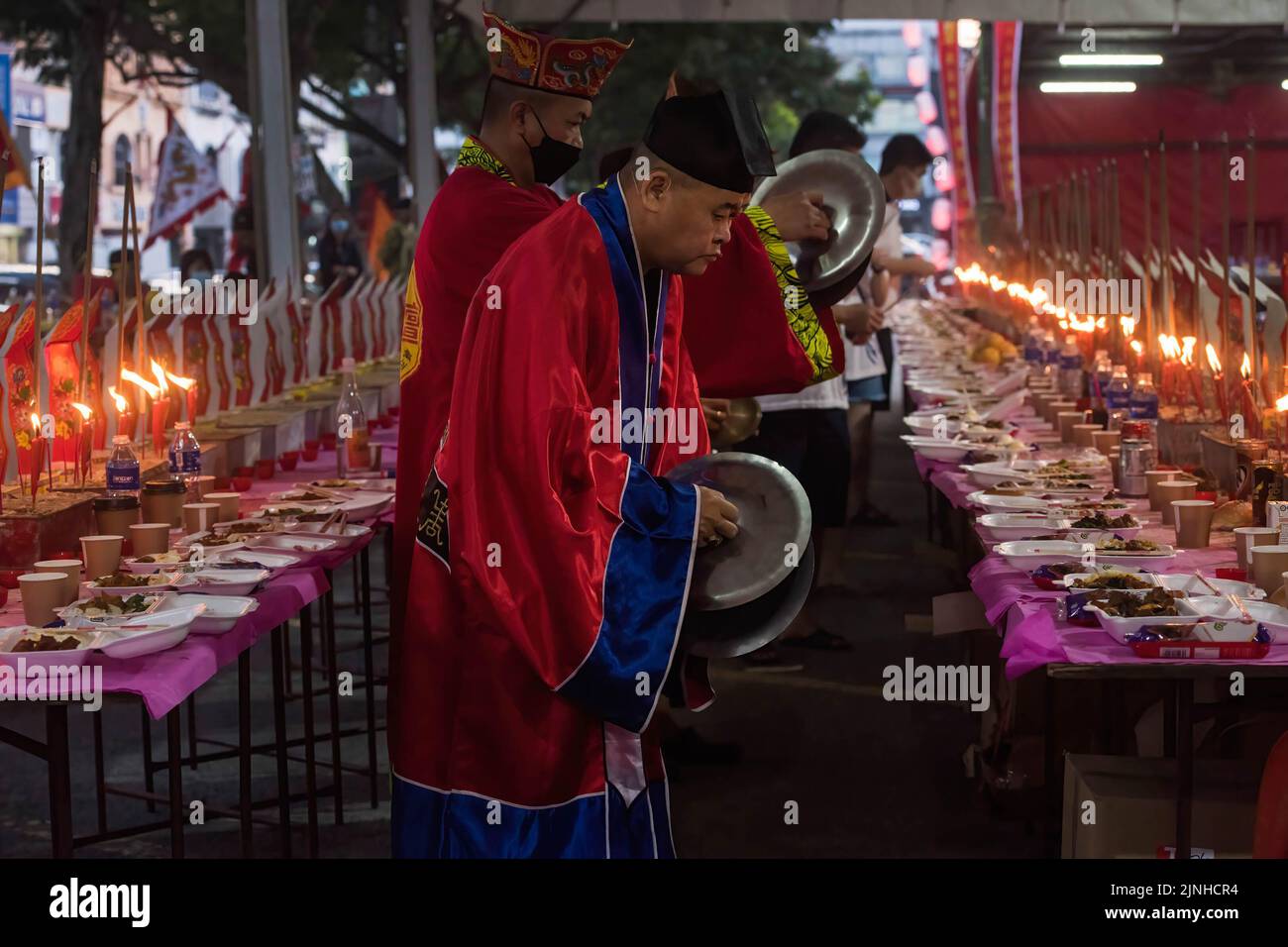 Ethnic Chinese priests offer prayers in front of the offerings for the ...
