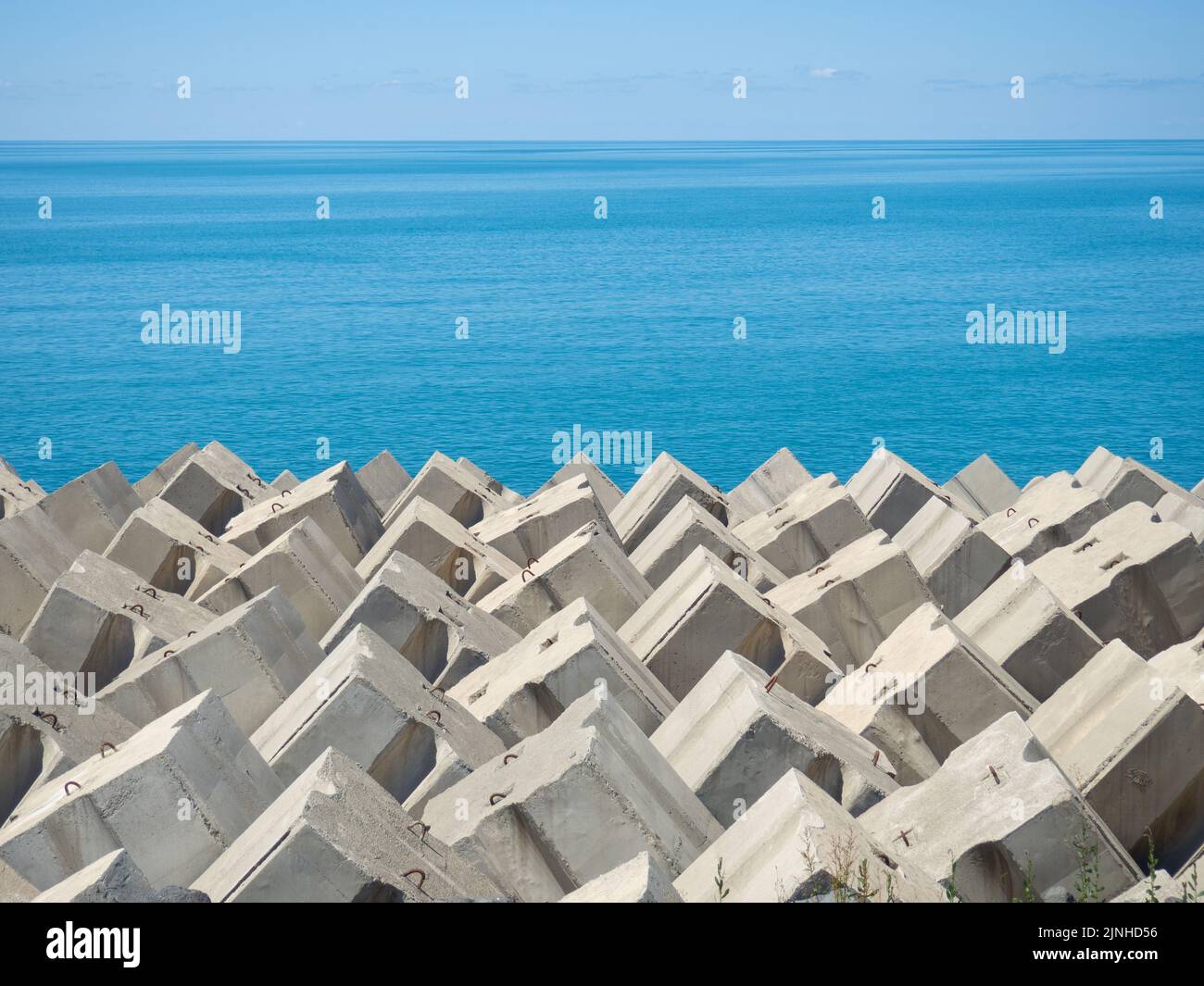 Concrete breakwaters and heaps of stones on the shore. Stone against ...