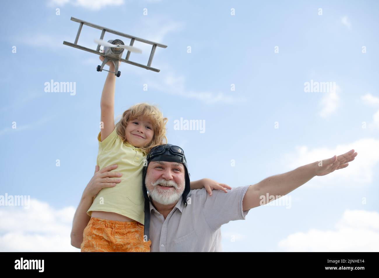 Grandfather and son having fun with plane outdoor on sky background ...