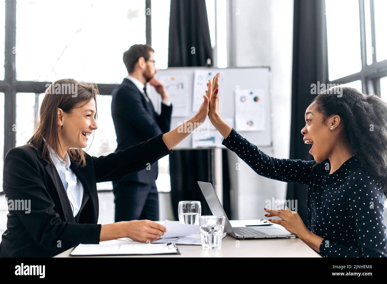Two successful multi-ethnic female colleagues work in a modern office ...