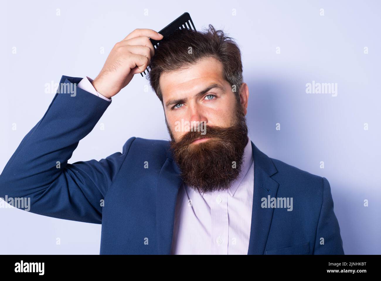 Man hairstyle, modern haircut. Man styling his hair with a comb ...