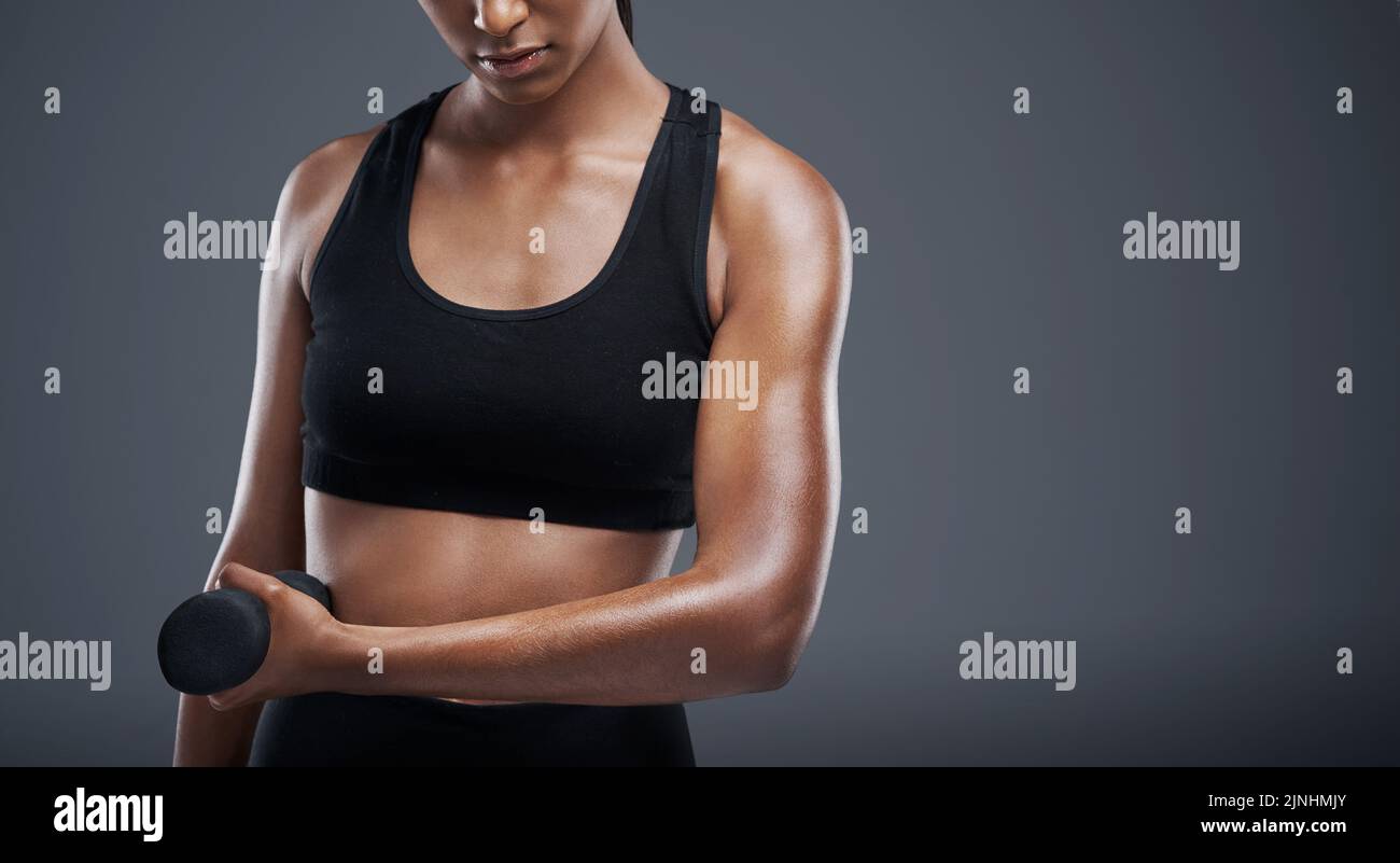 Make those biceps bulge. Studio shot of a sporty young woman lifting ...