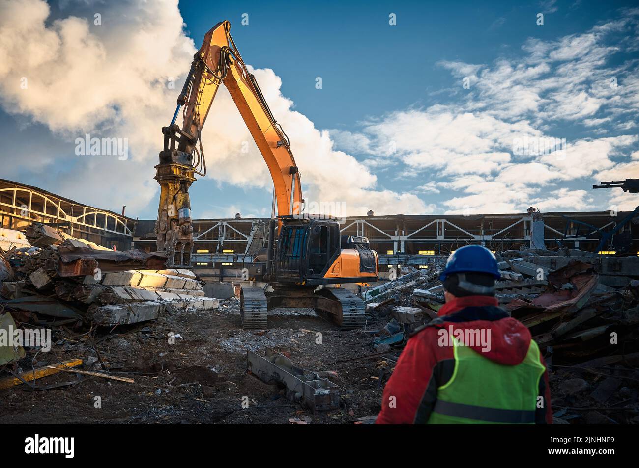 Excavator destroyer removes debris under worker control Stock Photo - Alamy