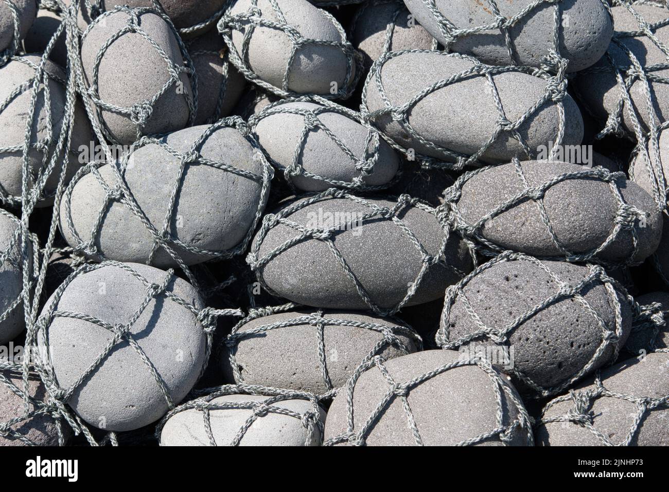 Grey rock weights tied with string Stock Photo - Alamy