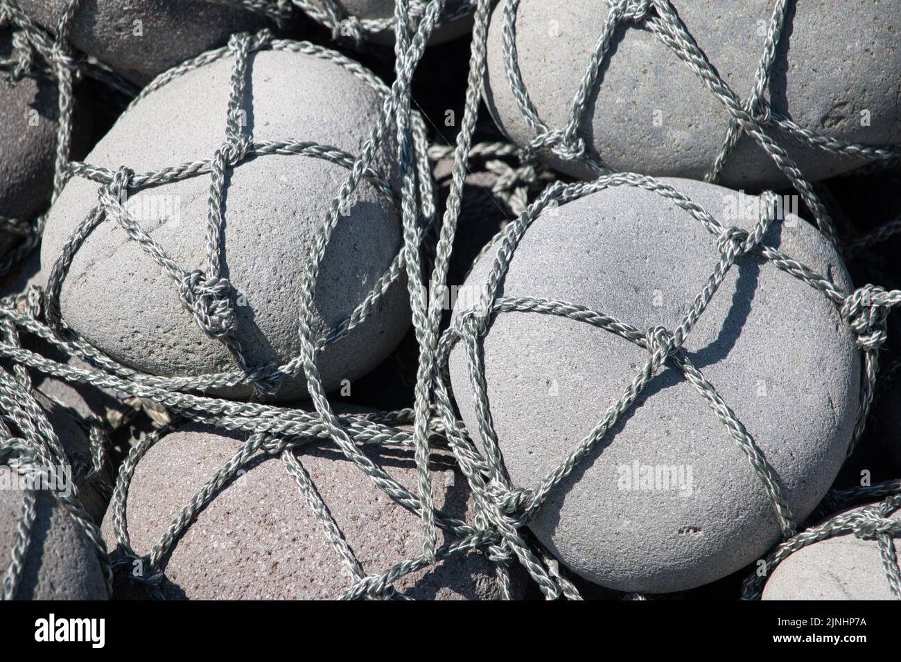 Grey rock weights tied with string Stock Photo - Alamy