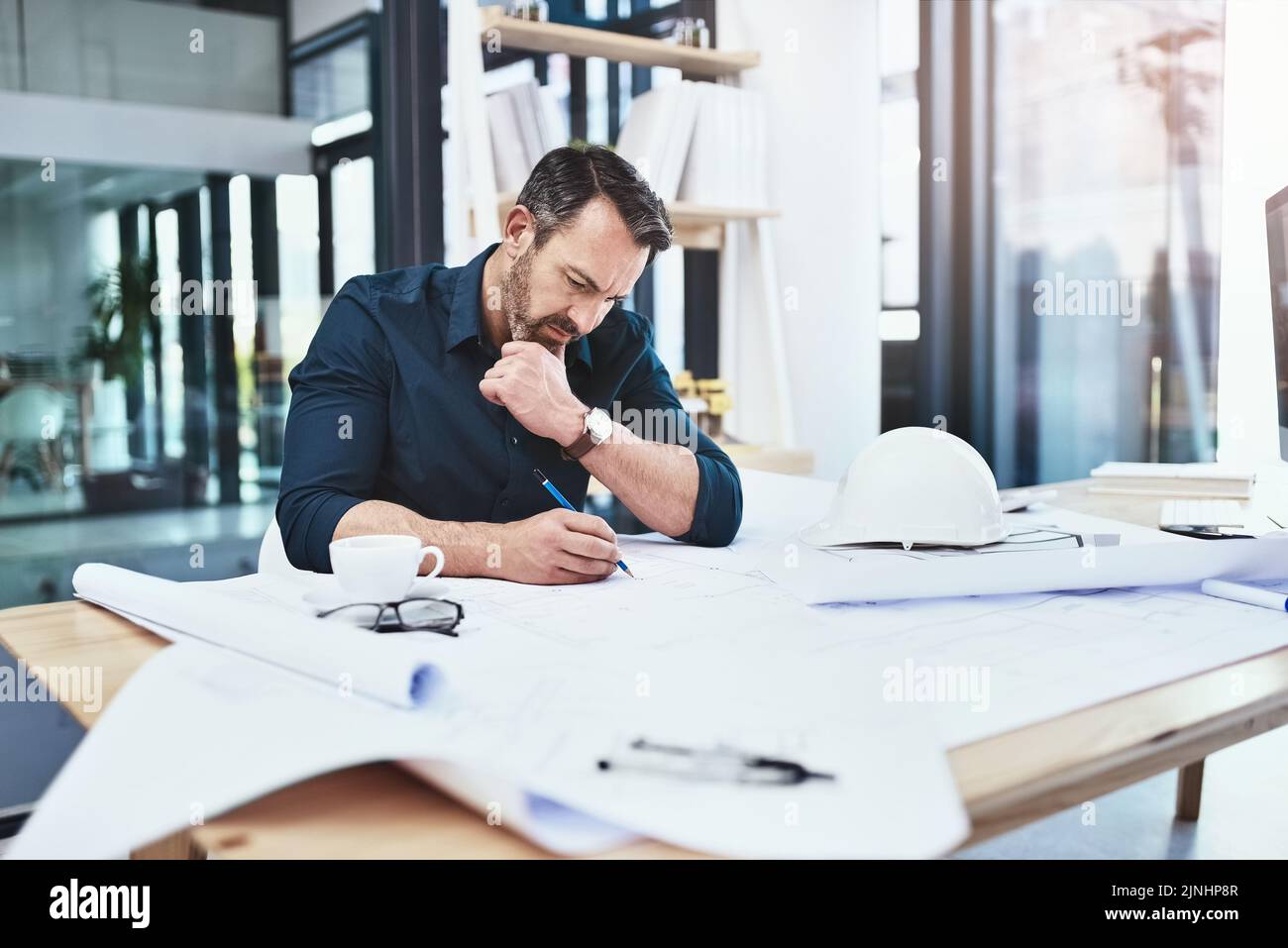 Working hard to meet his clients needs. a mature male architect working ...