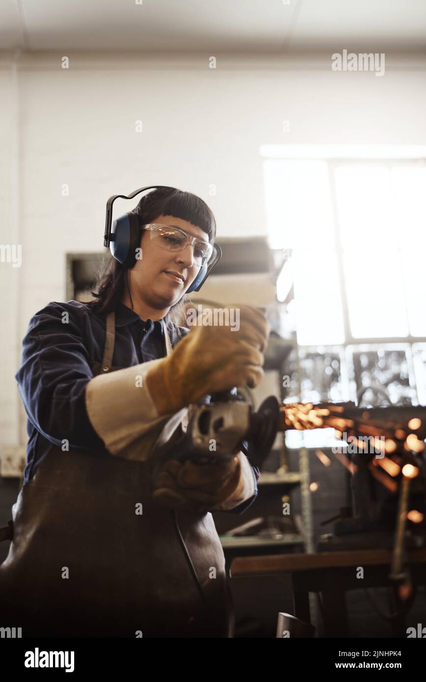 Cutting it to size. an attractive young female artisan using an angle ...