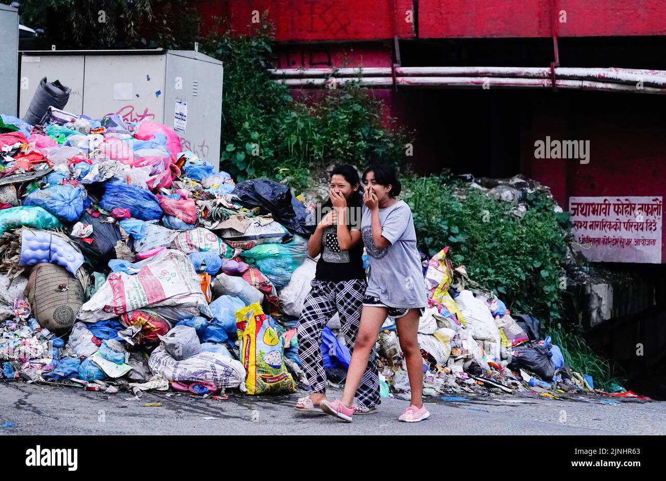 Kathmandu, Nepal. 11th Aug, 2022. People walk past uncollected heaps of ...