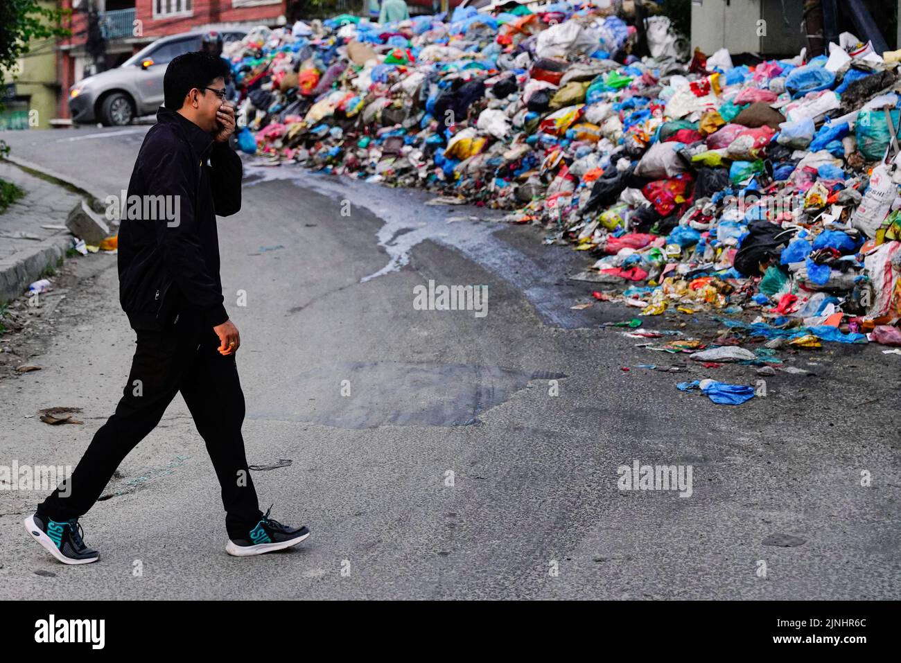 Kathmandu, Nepal. 11th Aug, 2022. A man walks past uncollected heaps of ...
