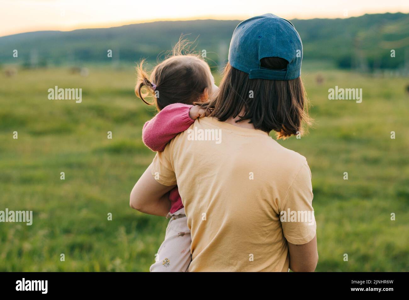 The mother walking with her child in her arms, looking at the green ...