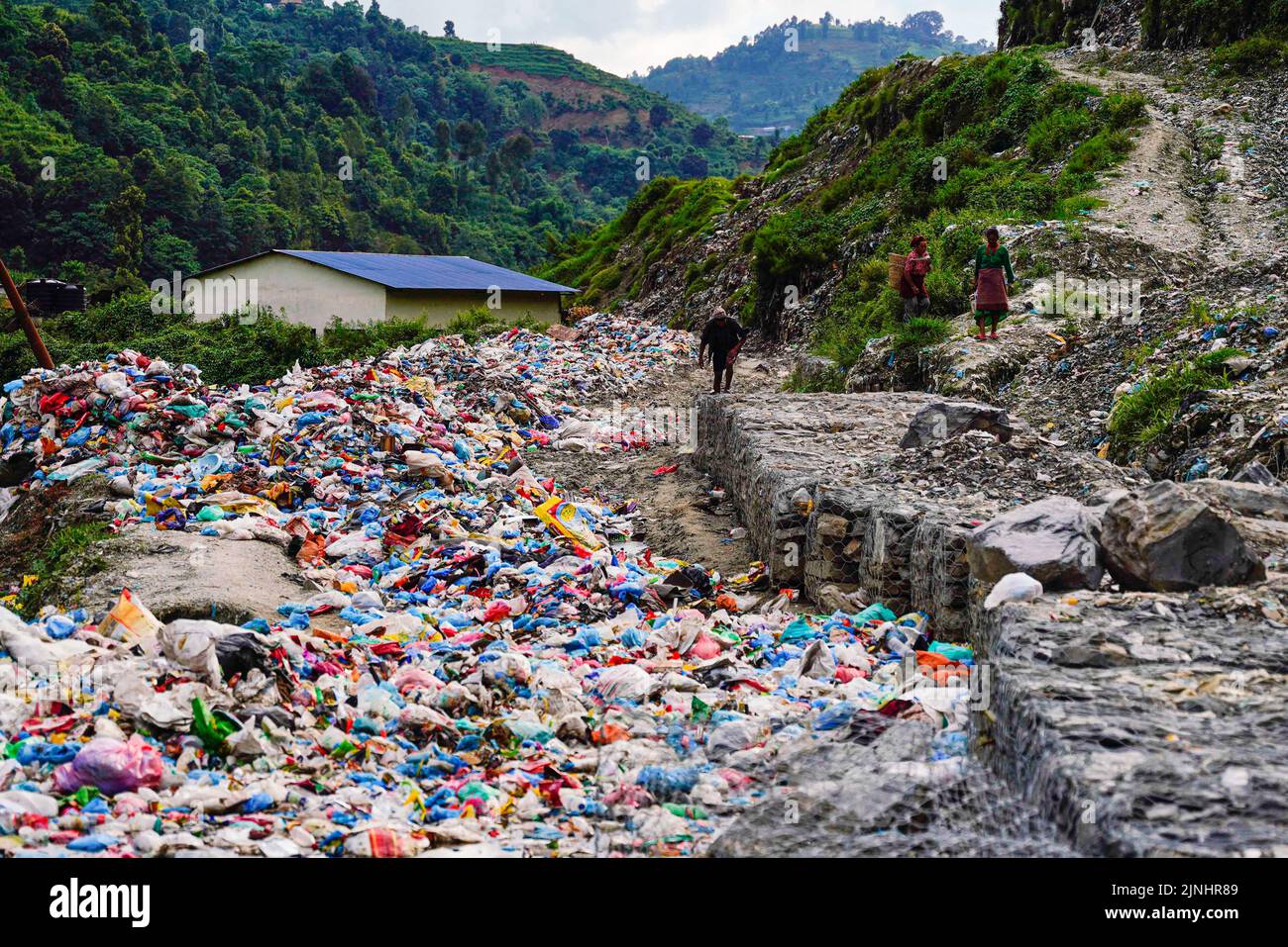 People walk along the highway filled with garbage near the waste ...