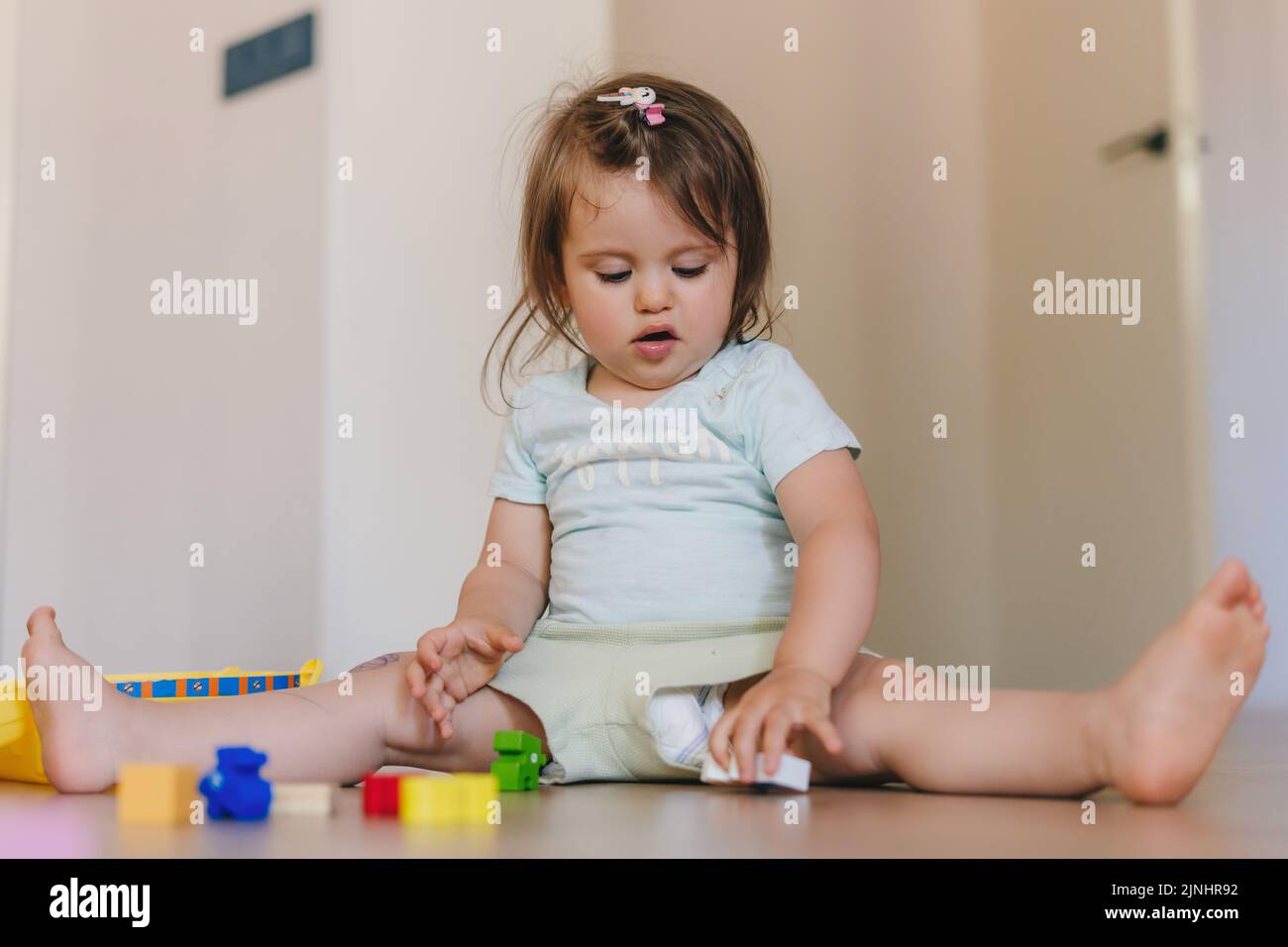 Baby girl building towers from small wooden blocks. Baby development ...