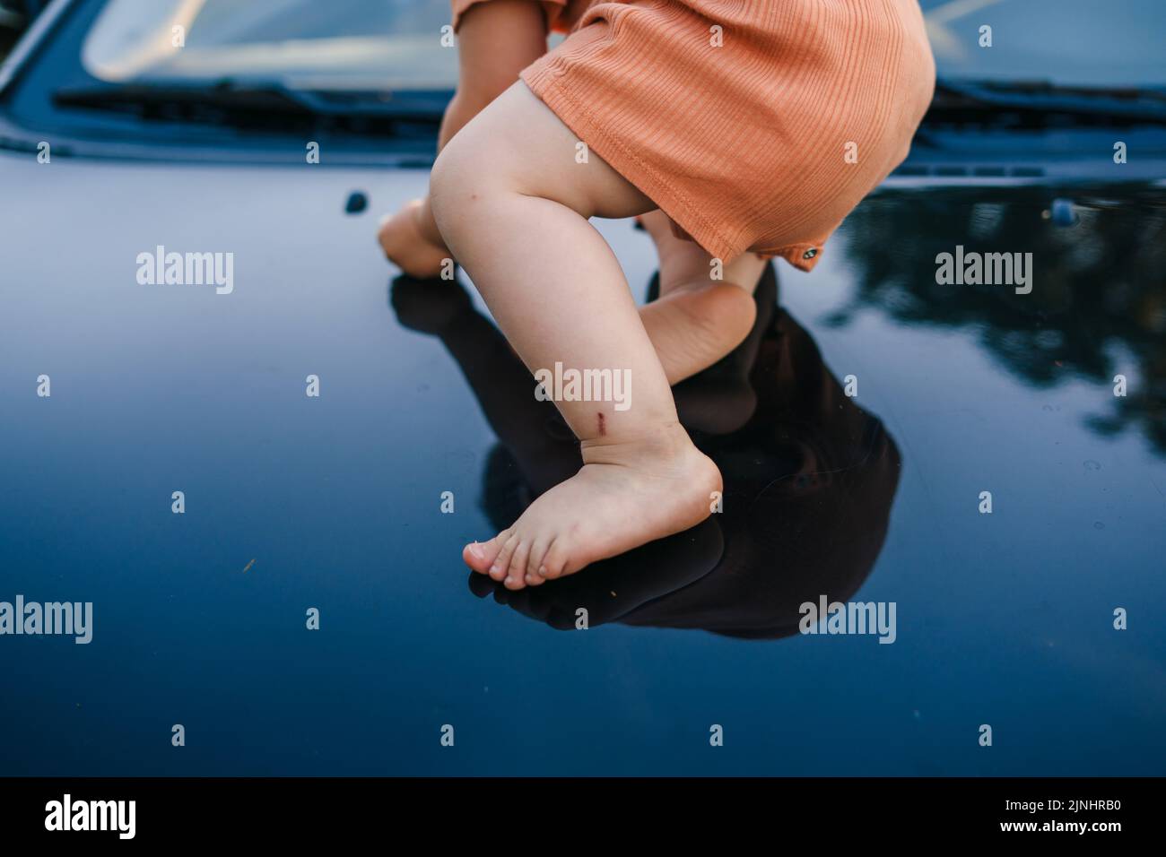 Close-up portrait of the feet of a baby trying to move are on the hood ...