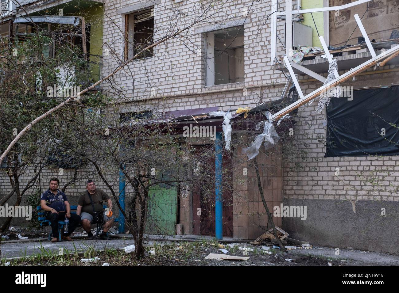 Residents seen sitting outside their apartment buildings damaged by the ...