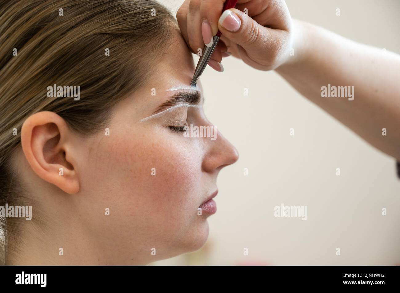 The master draws the shape of the eyebrows with white paint before ...
