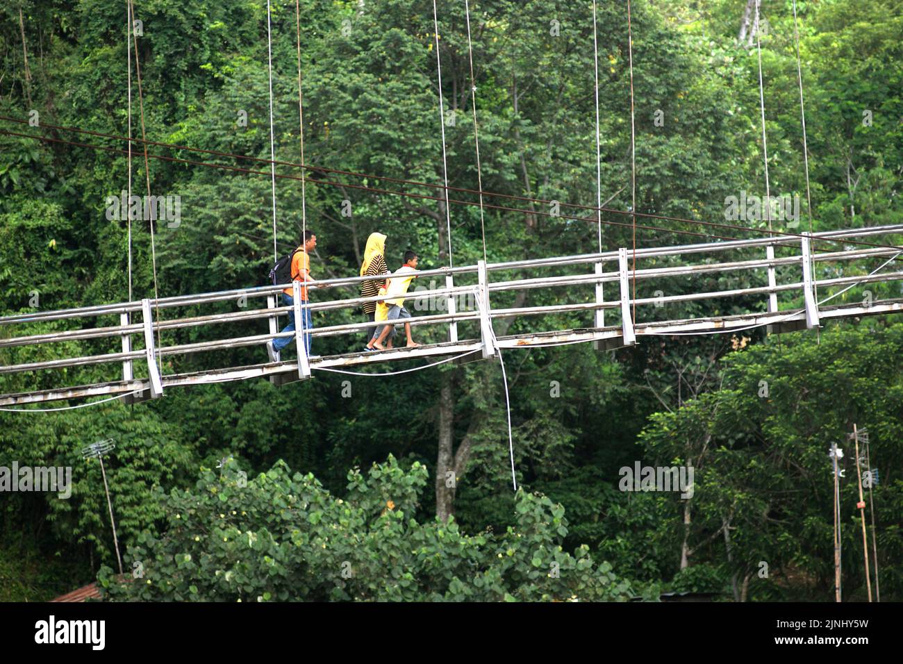 People walking on a hanging bridge, crossing over Bahorok river in ...
