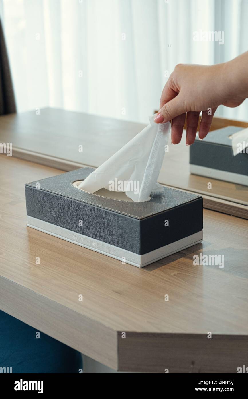 Woman hand picking up tissue paper from tissue box on makeup table ...