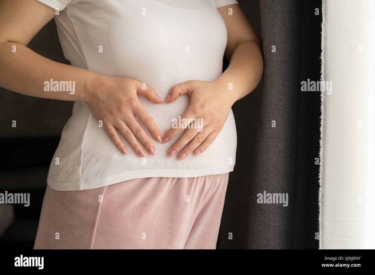 Beautiful young pregnant woman making a heart with her hands, pregnant ...
