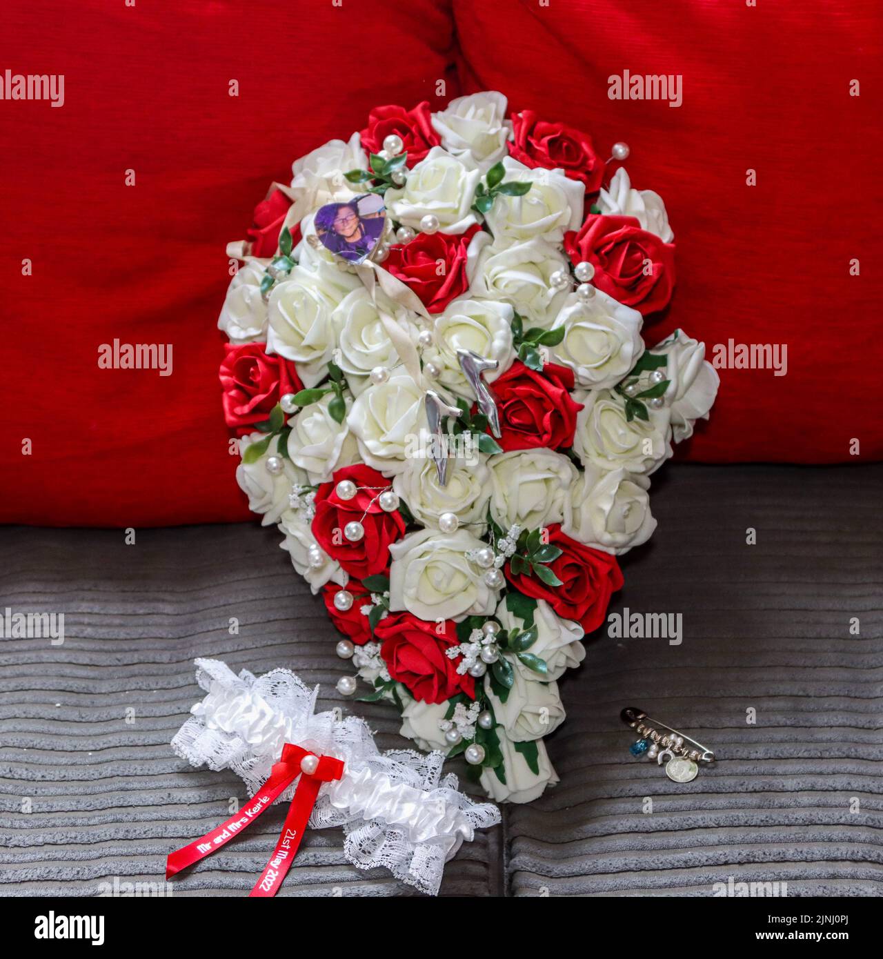 A beautiful bridal bouquet, white garter, and pin on a surface Stock ...