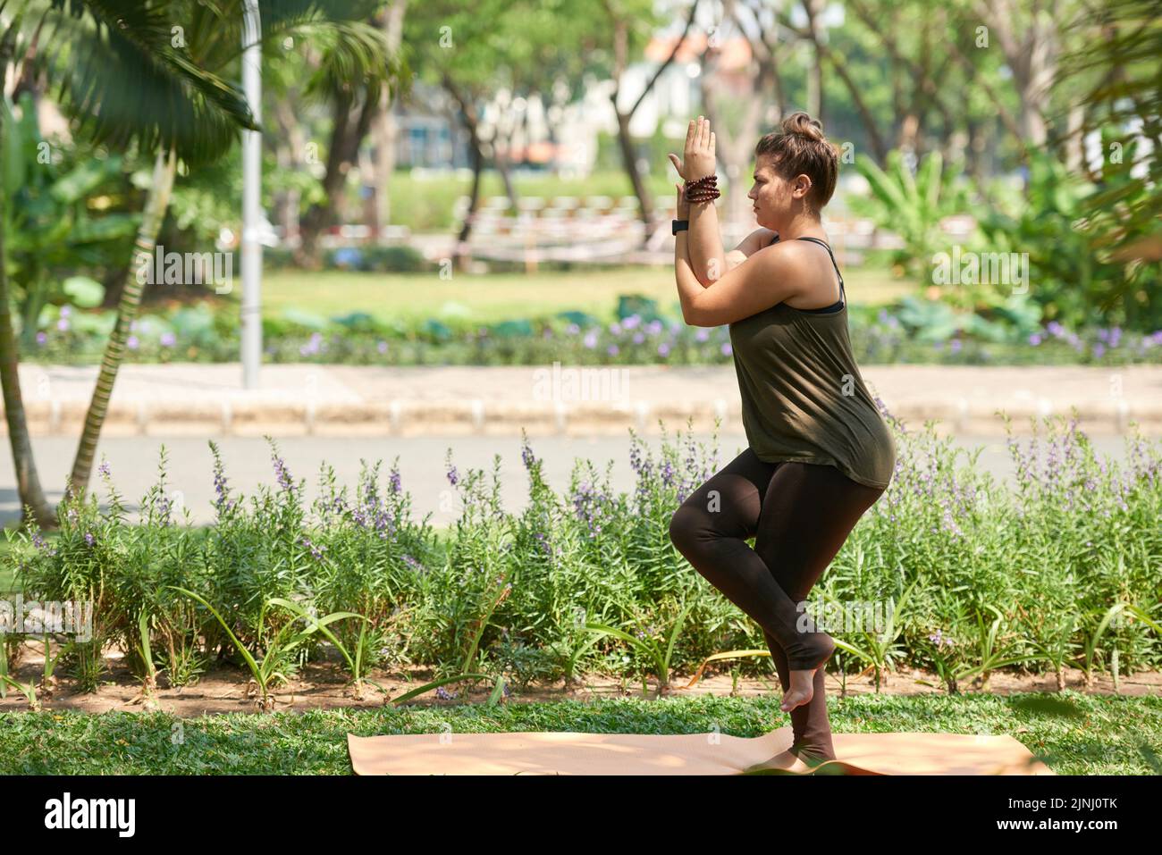 Profile view of young obese woman in sportswear practicing yoga at ...