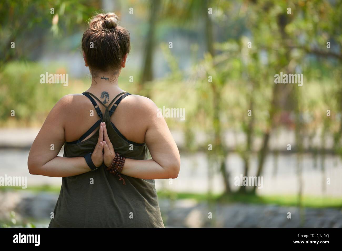 Back view of young fair-haired woman wearing top doing yoga while ...