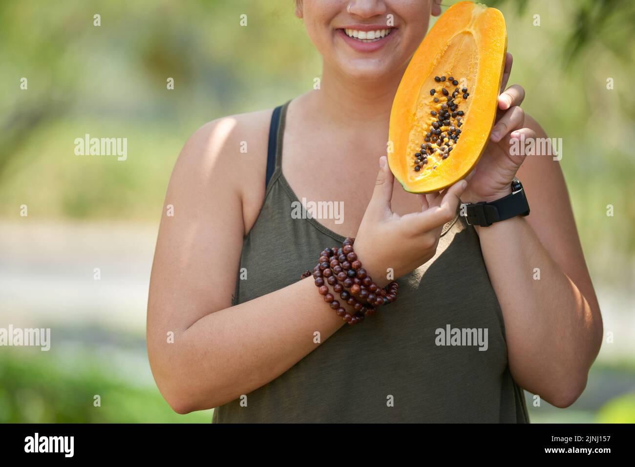 Unrecognizable young woman with charming smile standing at green public ...