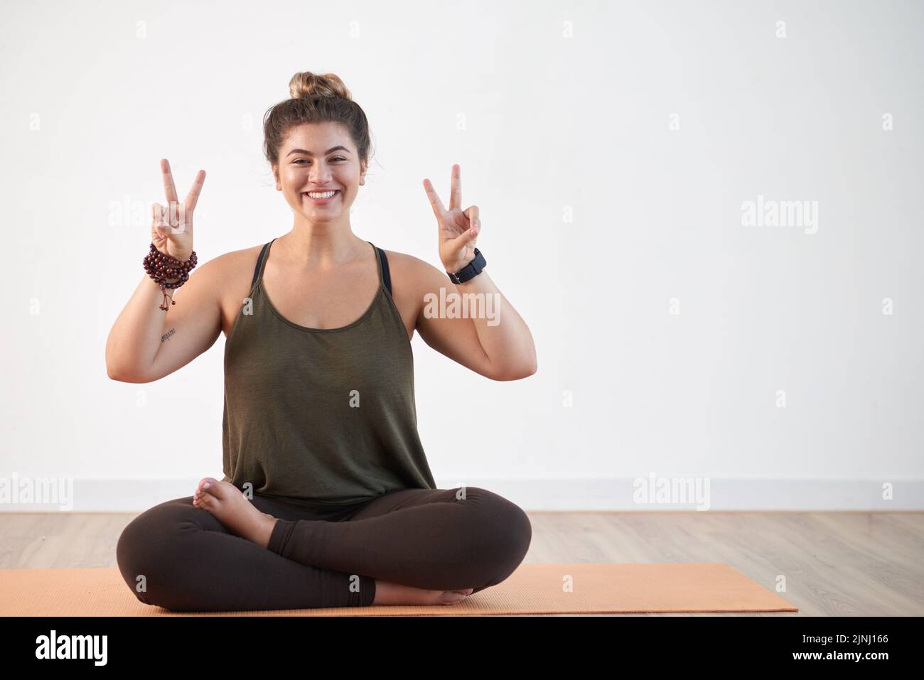 Full length portrait of cheerful young woman sitting in louts position ...