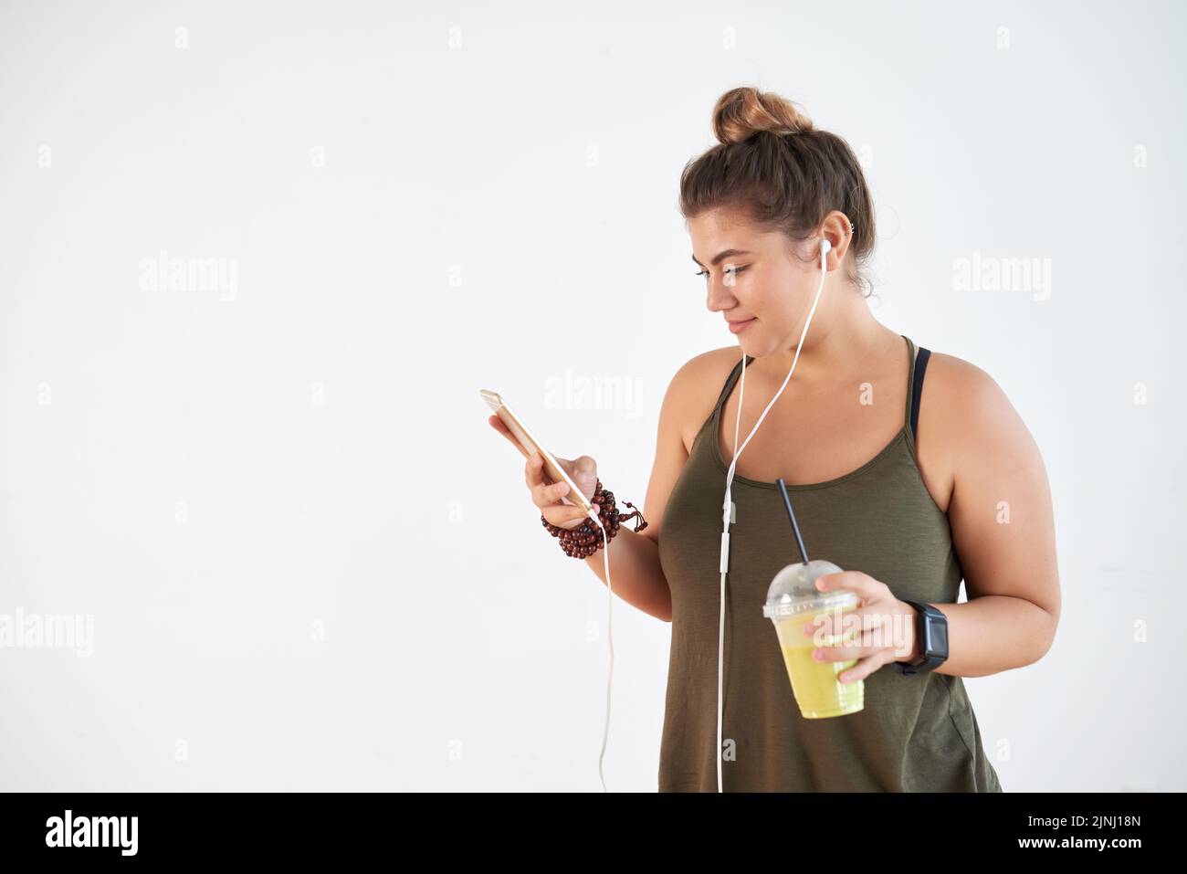 Pretty young woman listening to music with help of smartphone and ...