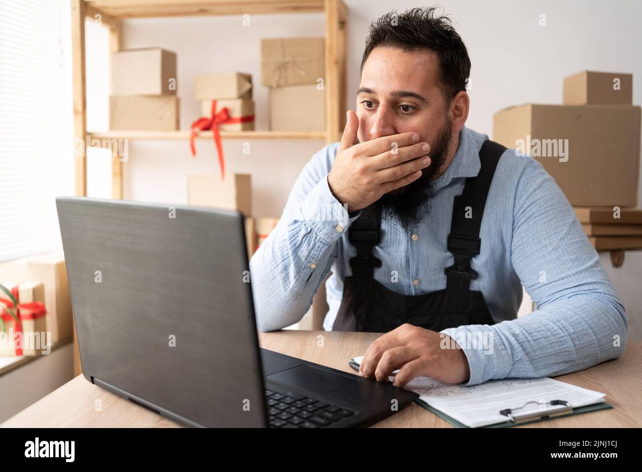 Nervous Indian man close mouth read amazing news on laptop computer ...