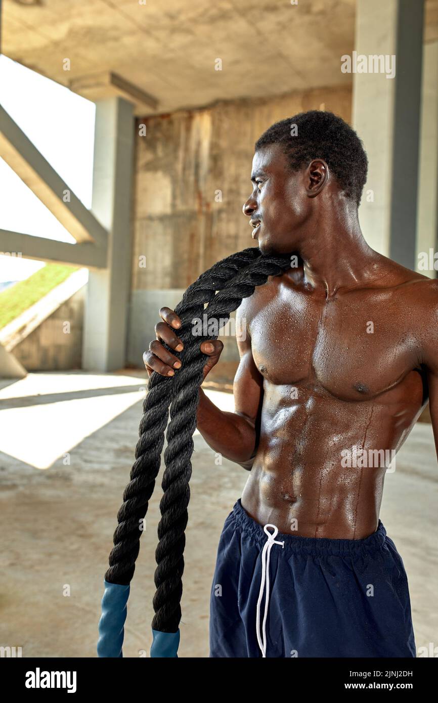 Rope workout. Sport man doing battle ropes exercise outdoor. Black male ...