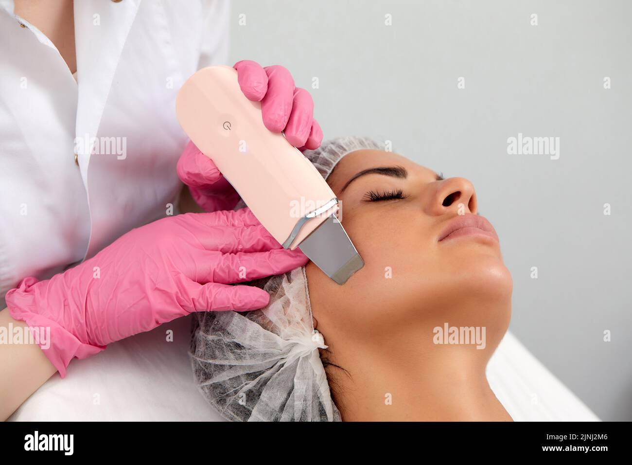 Beauty doctor with ultrasonic scraber doing procedure of ultrasonic ...